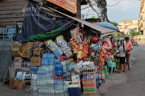 huge number of boxes of all sorts of drinks and food near a small shop ...