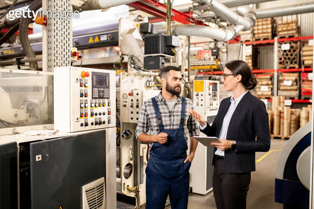 Two young business partners discussing working methods of industrial ...