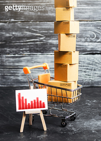Boxes in a shopping cart and a easel with negative trend chart ...