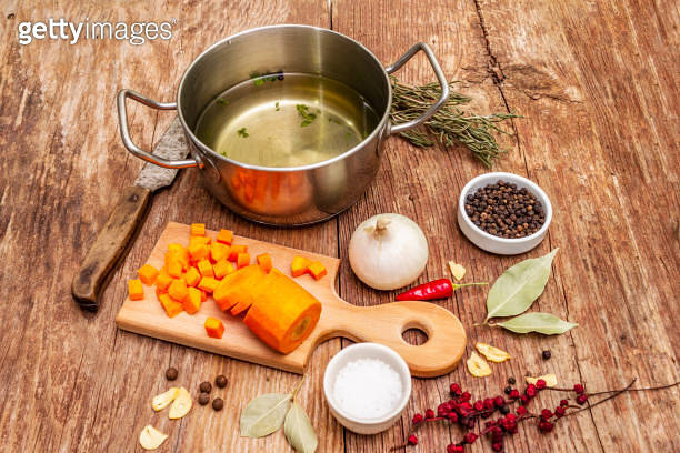 Transparent duck broth in pan with fresh ingredients. Traditional ...