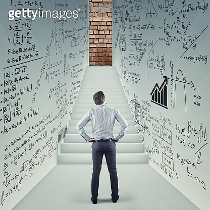 Businessman in a hall trying to solve math problem drawn on walls ...
