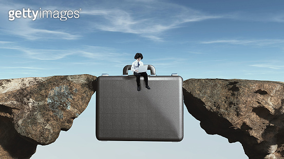 Man working on laptop and sits on a briefcase between two rocks. Make ...