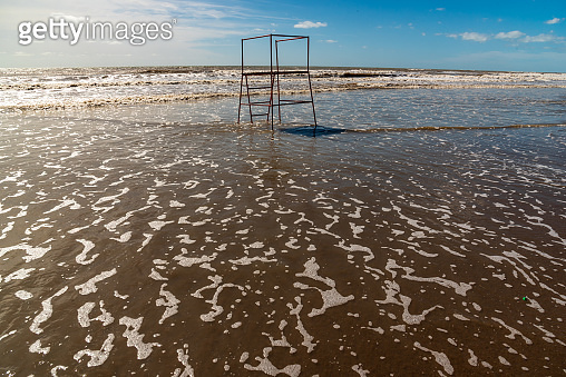 Empty beach with high tide with a red lifeguard stand made of tubes ...