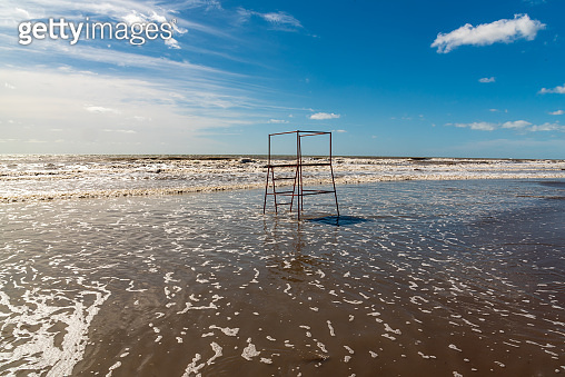 Empty beach with high tide with a red lifeguard stand made of tubes ...