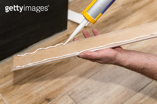 Using caulking gun to install white skirting board 이미지 (1160956329 ...