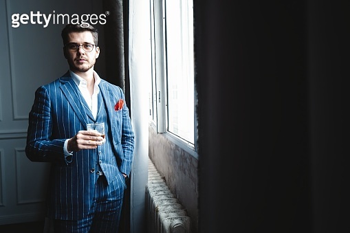 Real macho. Handsome young man in suit looking at camera and smiling ...
