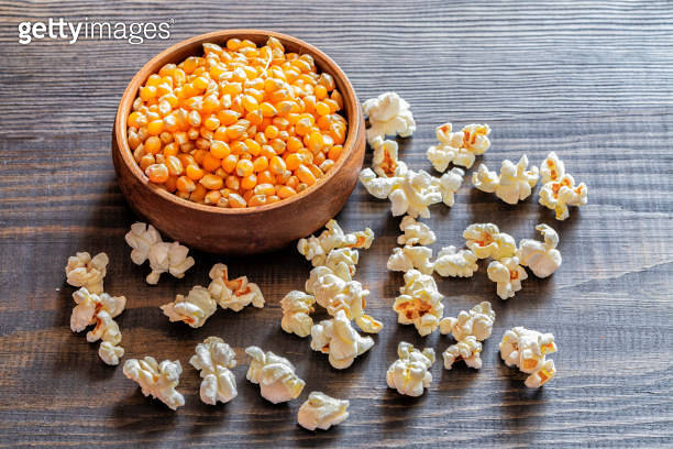 On wooden insulated floor, fresh corn, dry corn grains, popcorn grains ...