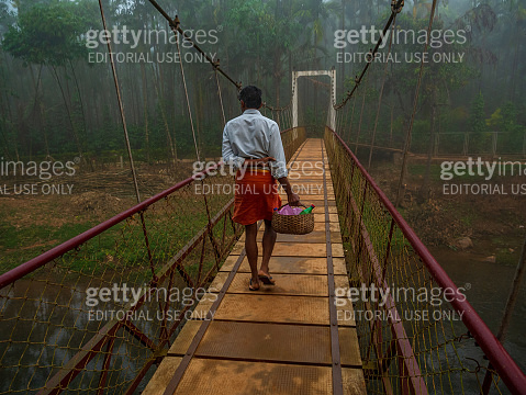 South indian man walking in a traditional Lungi on a Hanging bridge ...
