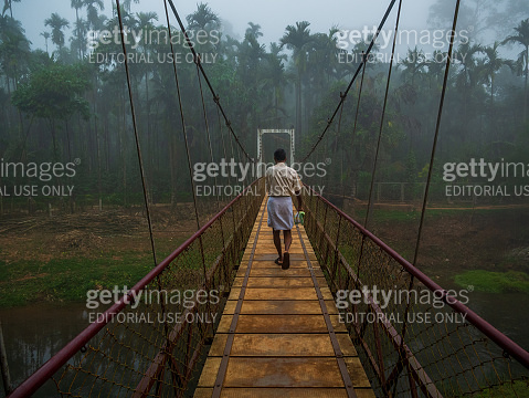 South indian man walking in a traditional Lungi on a Hanging bridge ...