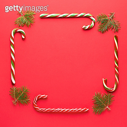 Rectangular frame from candy canes and fir tree on red background ...