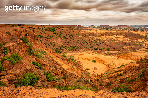 Vividly colored sahel landscape with ravines, rocks and sand with ...