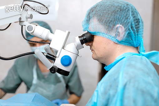 ophthalmologist surgeon looking through surgical microscope doing ...