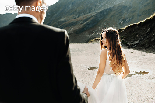 Lovely young caucasian bride leading his groom by holding hands and ...