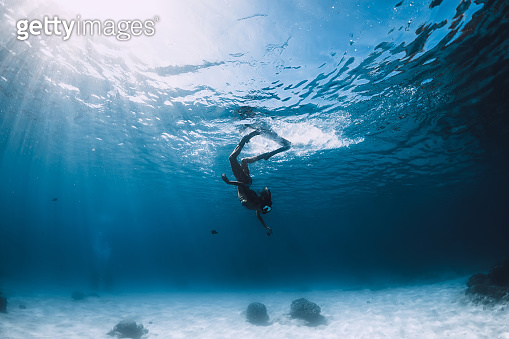 Woman freediver with fins underwater. Freediving and beautiful light in ...