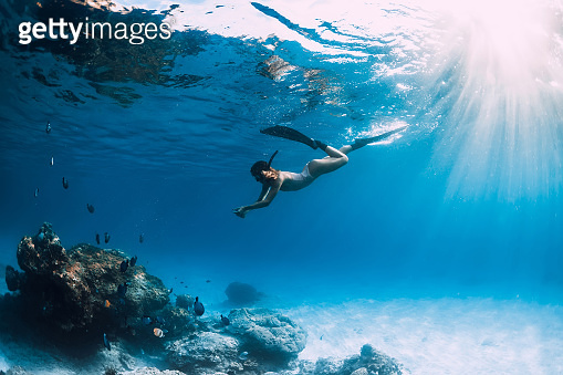 Woman freediver with fins underwater. Freediving and beautiful light in ...