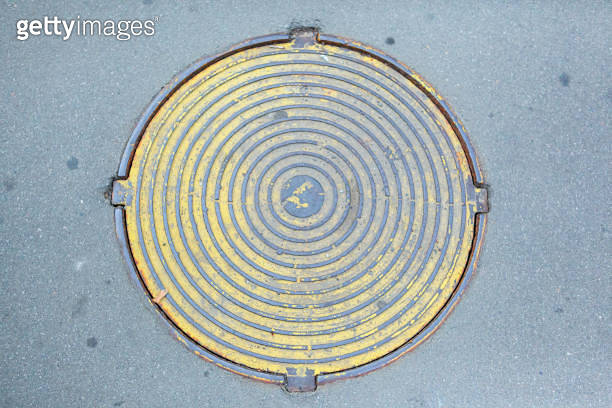 Round sewer manhole cover in urban asphalt pavement (1166431685) - 게티이미지뱅크