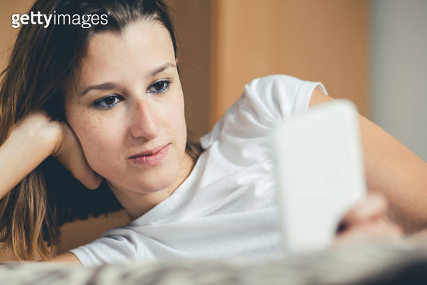 Woman lying on bed and using mobile phone. 이미지 (1139619609) - 게티이미지뱅크