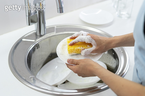 Woman using sponge with foam, washing plate in sink at white kitchen ...