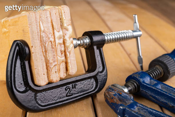 Glued pieces of wood and carpentry clamp on a wooden table. Carpentry ...