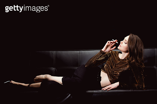 beautiful glamorous woman lying on couch and smoking cigarette isolated ...