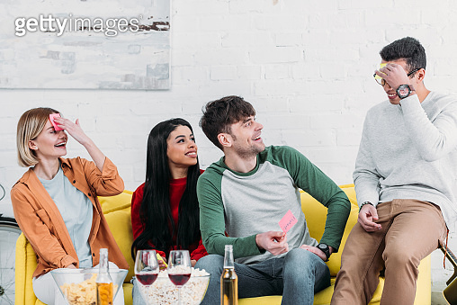 multiethnic friends having fun at home party and fixing stickers to ...