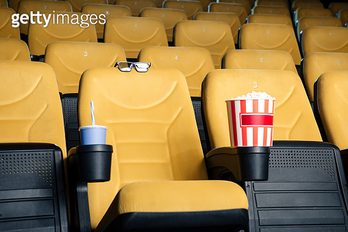 yellow cinema seats with paper cups of soda and popcorn in cup holders ...
