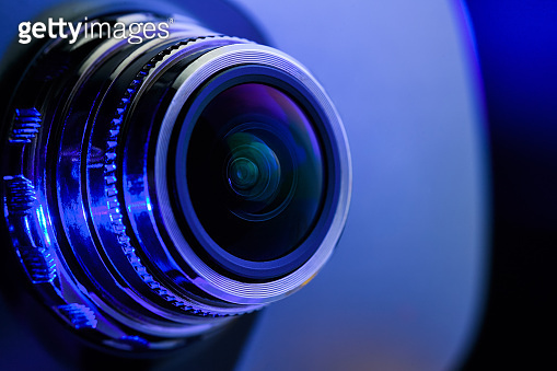 Camera lens with blue light. Side view of the lens of camera on blue ...