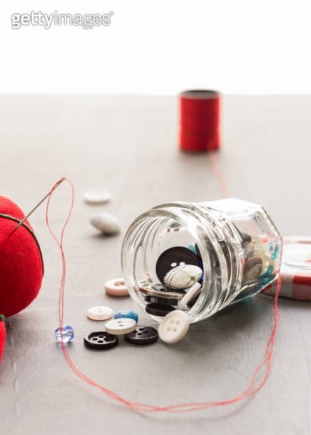 Set of buttons, thread and needle scattered on the table 이미지 ...