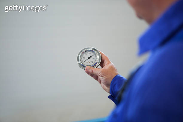 Details with the hand of a worker holding a broken glass PSI manometer ...
