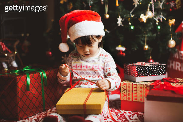 toddler girl getting christmas gift in front of christmas tree 이미지 ...