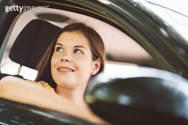 Beautiful smiling woman sitting in the car looking out the window 이미지 ...