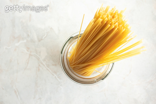 Long spaghetti ready to cook in glass jar, top view. Ingredient for ...