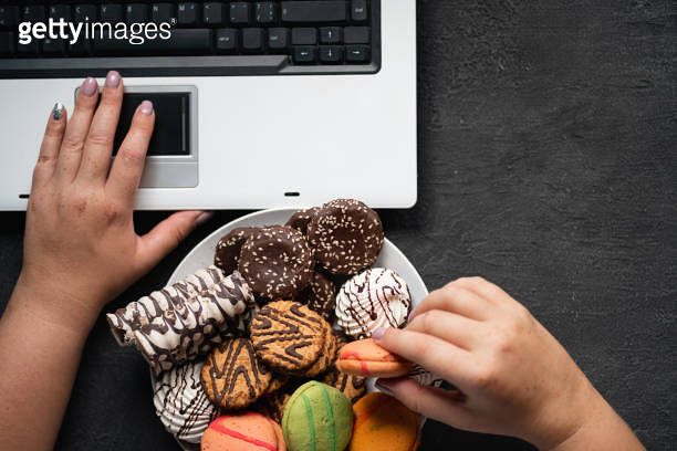 Woman eating cookies and coffee at workplace 이미지 (1165291444) - 게티이미지뱅크