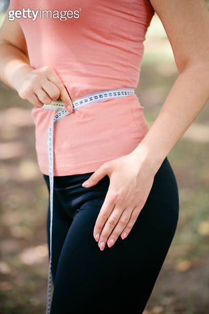 Woman with slim body measuring her waistline 이미지 (1164678749) - 게티이미지뱅크
