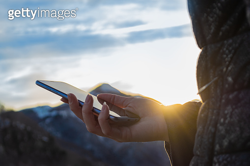 Close up of person holding smartphone outdoors during sunset, with ...