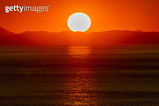 Beautiful golden sunset/sunrise over the sea behind mountains in ...