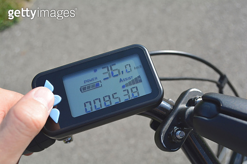 A male hand presses a button on a black electronic bicycle scooter ...