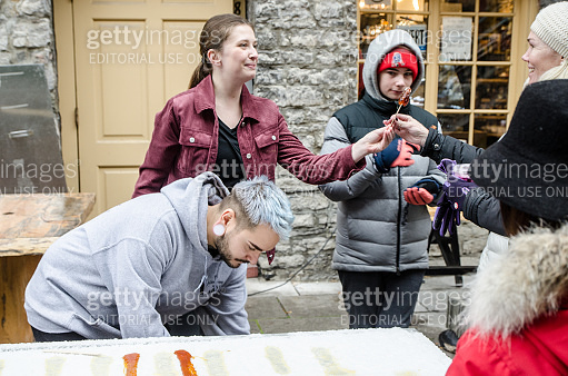 Woman giving frozen maple syrup on a stick (1187037988) - 게티이미지뱅크