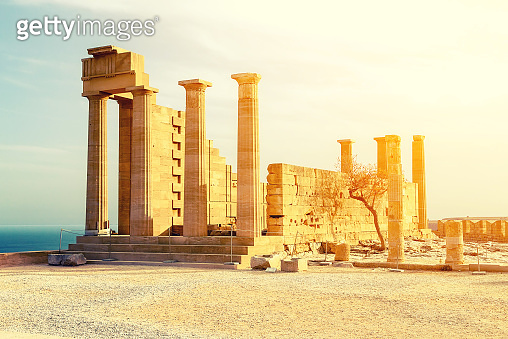 Ancient Greek acropolis. Front view of columns and walls. near the tree ...