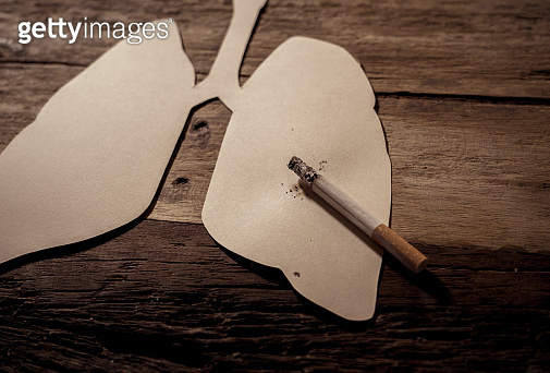 Conceptual image of cigarette burning on paper lungs isolated on rustic ...