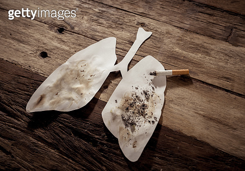 Conceptual image of cigarette burning on paper lungs isolated on rustic ...