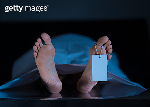 Close-up of dead body feet at morgue or hospital with toe label or ...