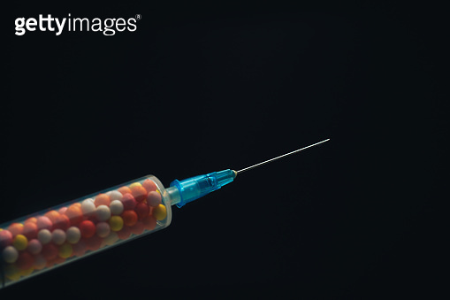 Syringe filled with colorful nano balls on a black background ...