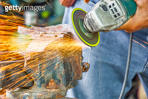 Close up hand and electric wheel grinding on steel structure in factory ...