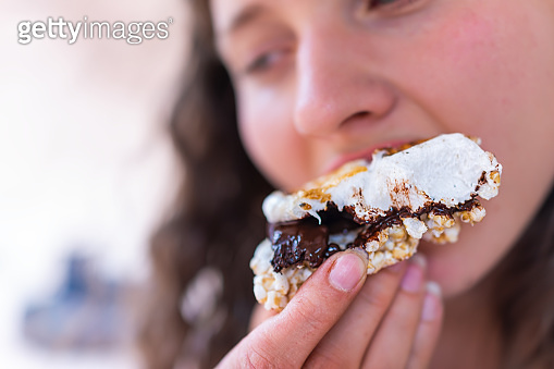 Closeup macro of young girl eating gooey roasted marshmallows smores ...
