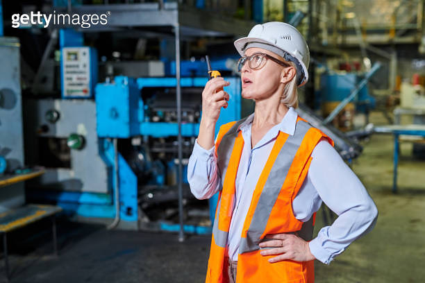 Serious confident female manufacturing manager in hardhat and safety ...
