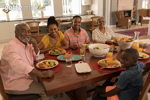 Multi-generation family having meal together on dining table at home ...