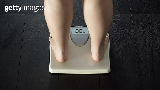 Extra weight problem, overweight female standing on scales, obesity ...