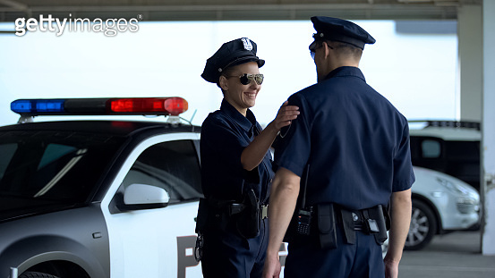 Positive male and female police officers communicating on parking lot ...