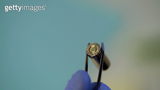 Gun bullet in tweezers examined by criminalist closeup, ballistics ...